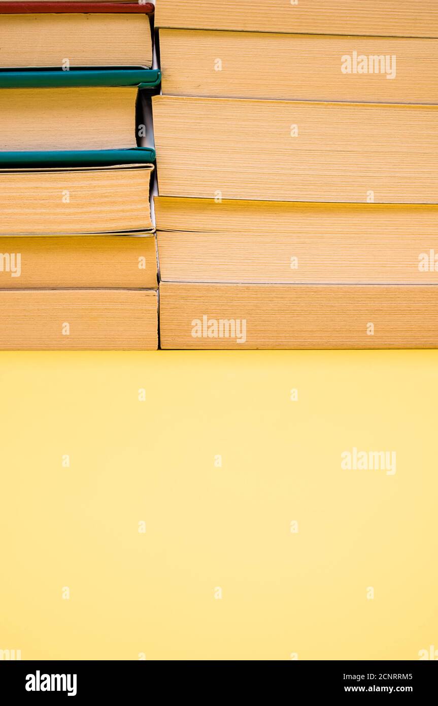 Books stack on top of each other on a yellow background Stock Photo - Alamy