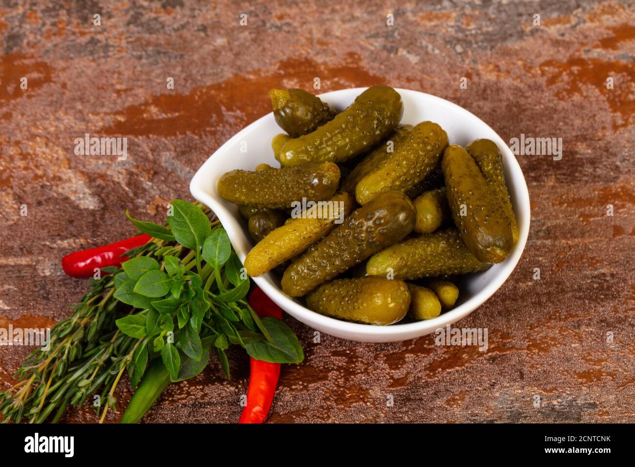 Pickled small cucumbers in the bowl served herbs Stock Photo - Alamy