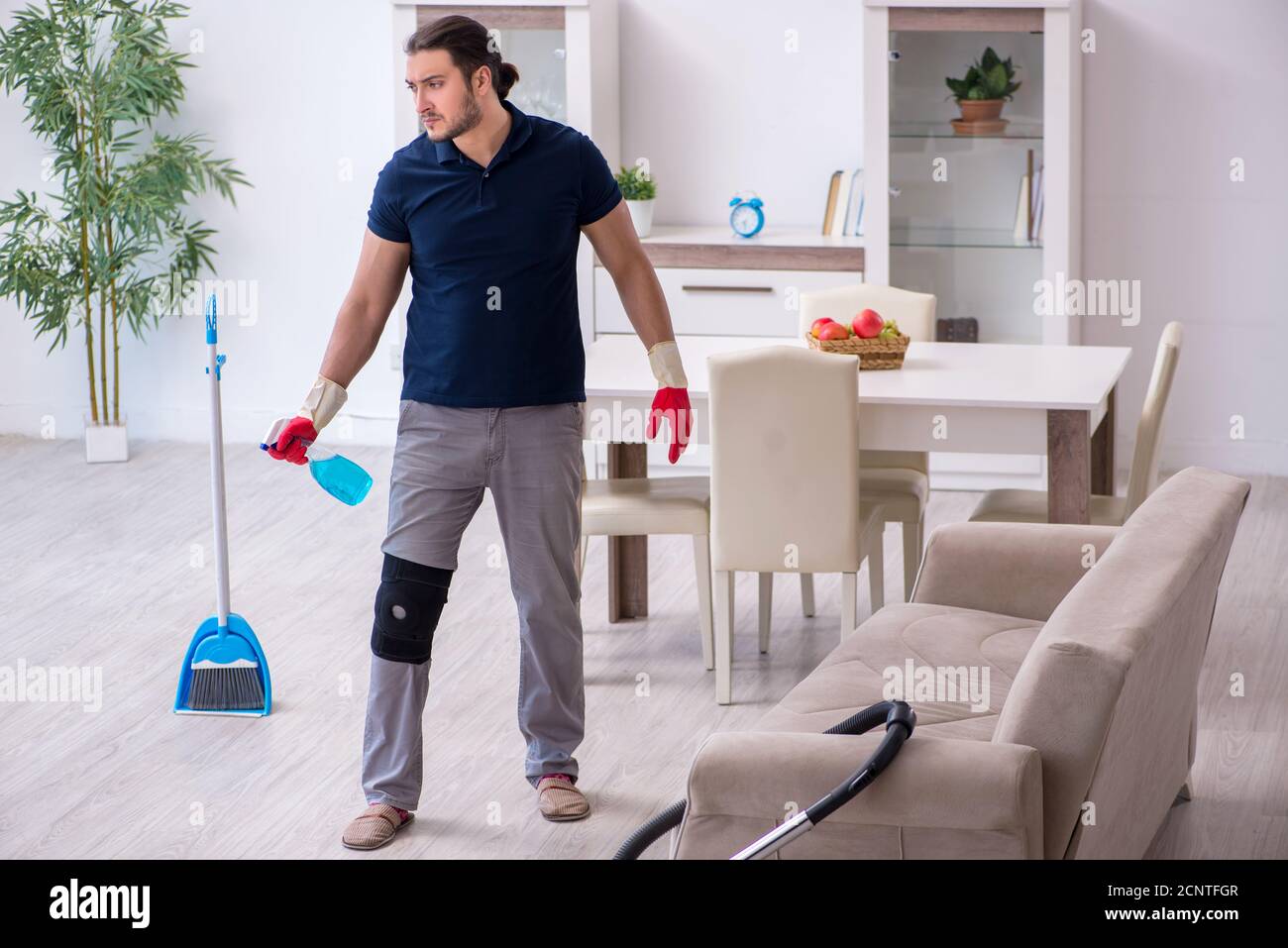 Young leg injured contractor cleaning house Stock Photo - Alamy