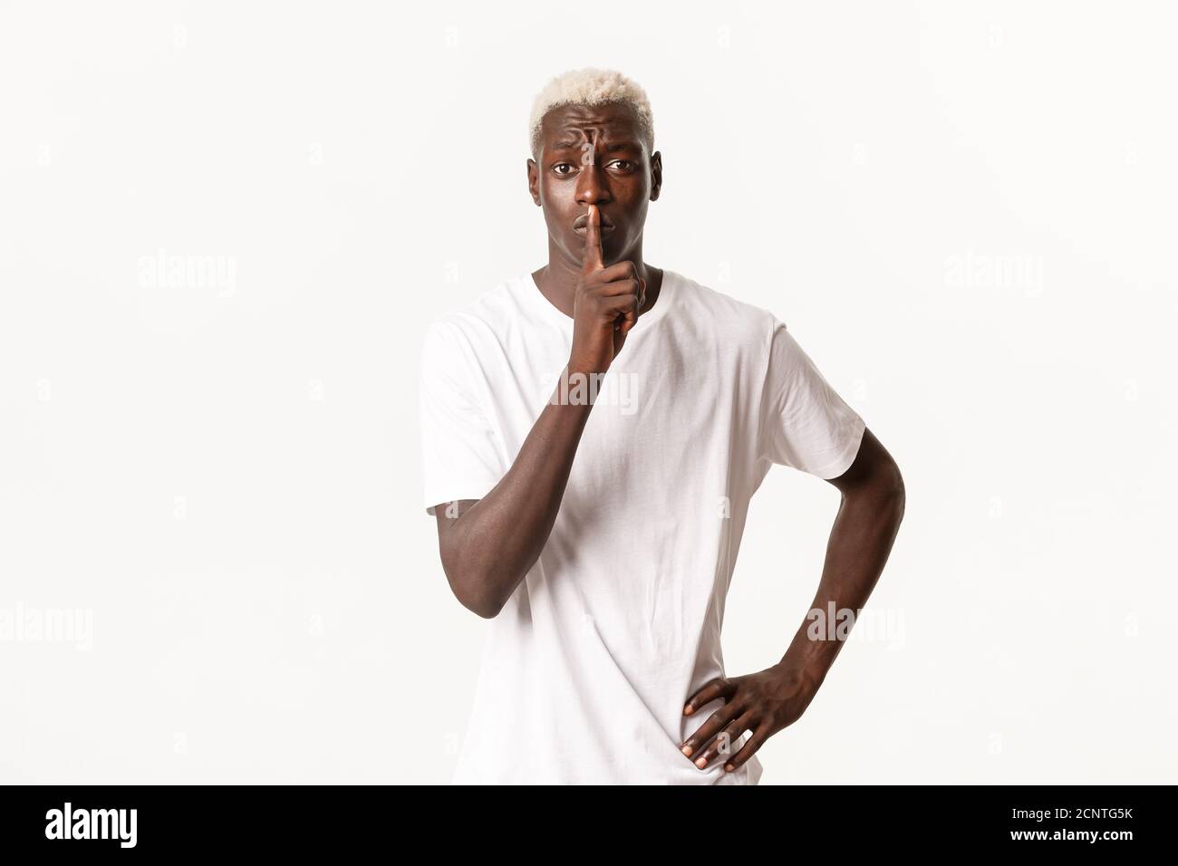 Portrait of concerned african-american blond man, shushing at camera ...