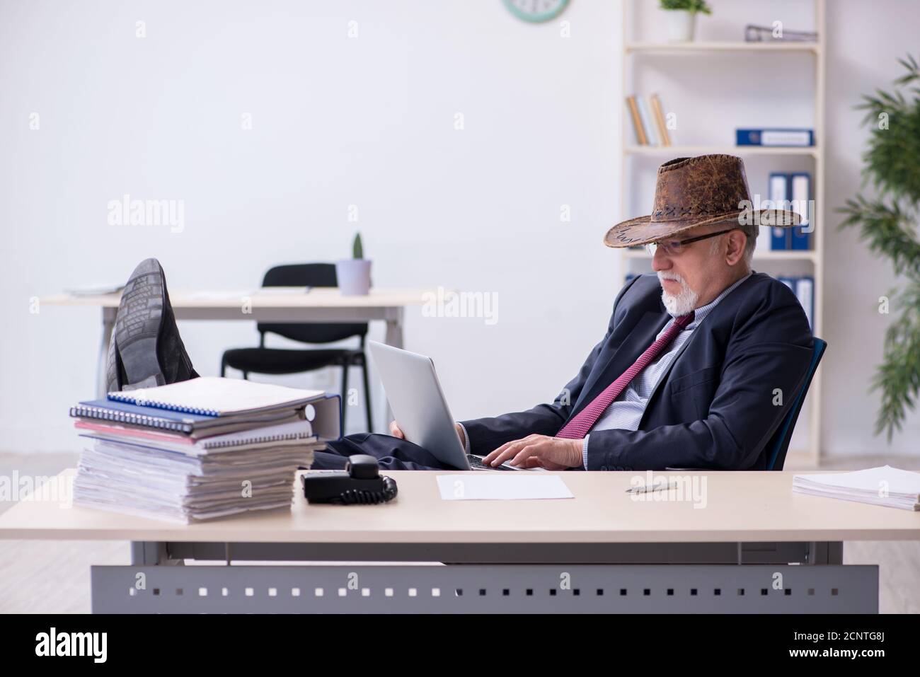 Funny old boss in cowboy hat in office Stock Photo - Alamy
