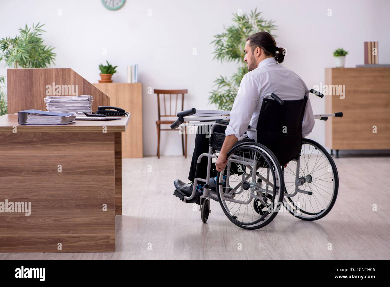 Young disabled employee suffering at the workplace Stock Photo - Alamy