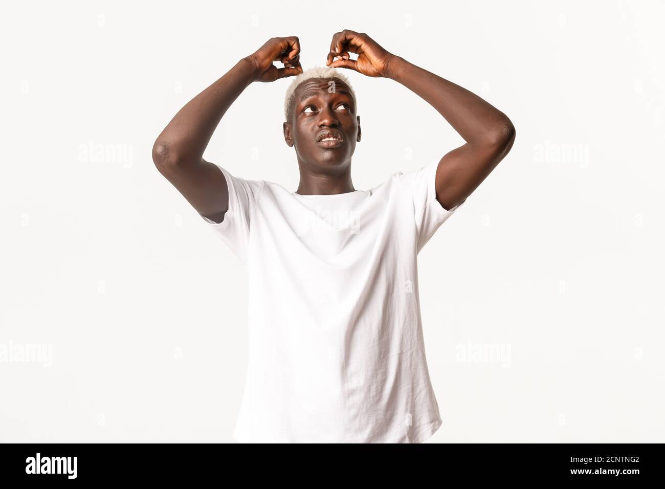 Portrait of confused african-american guy looking at his new blond hair ...