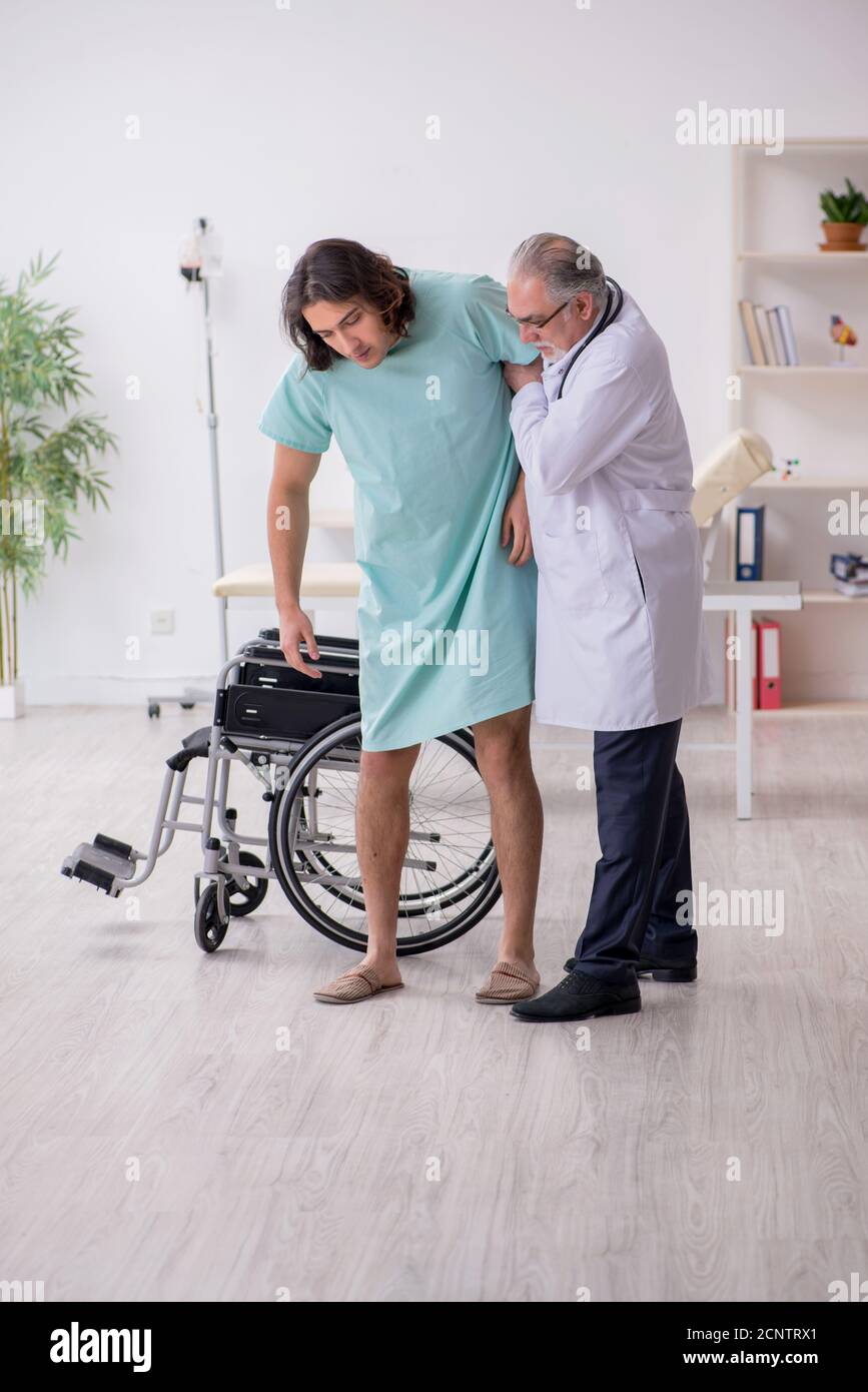 Young patient in wheel-chair and experienced doctor traumatologist ...