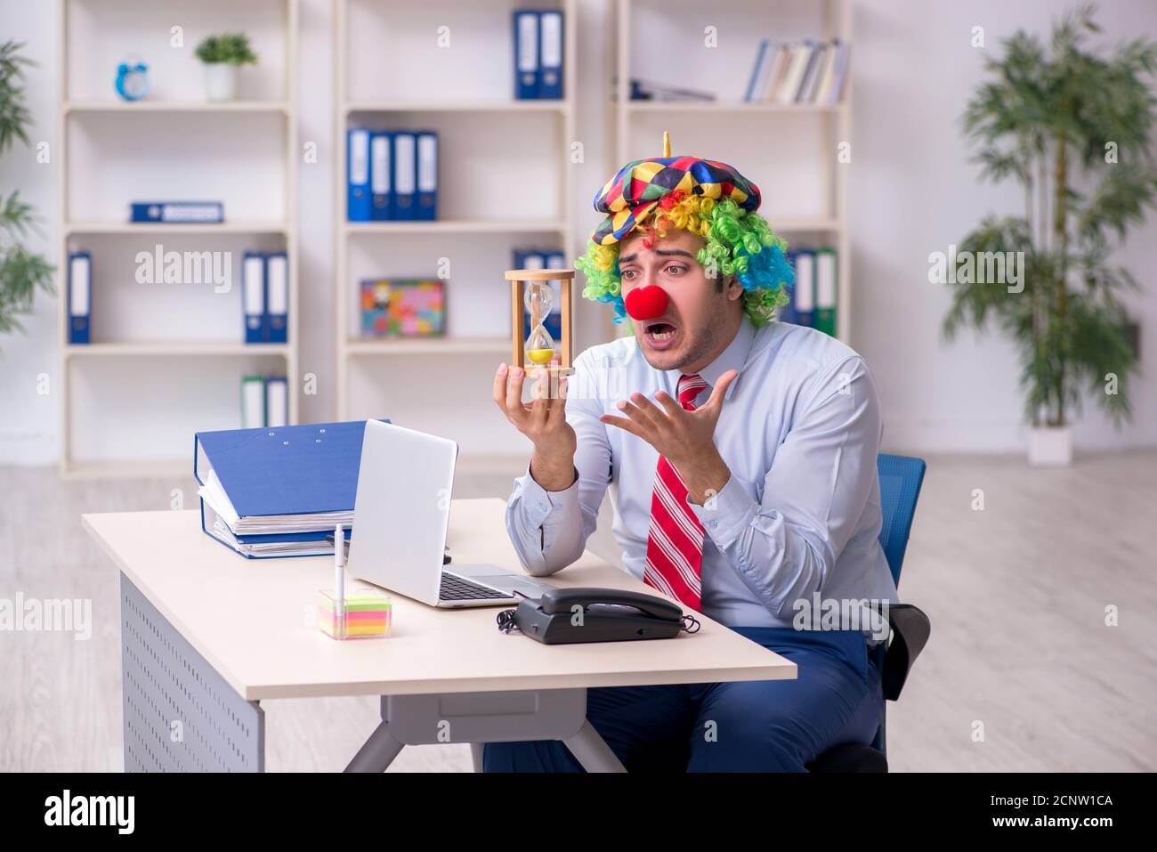 Funny employee clown working in the office room Stock Photo - Alamy