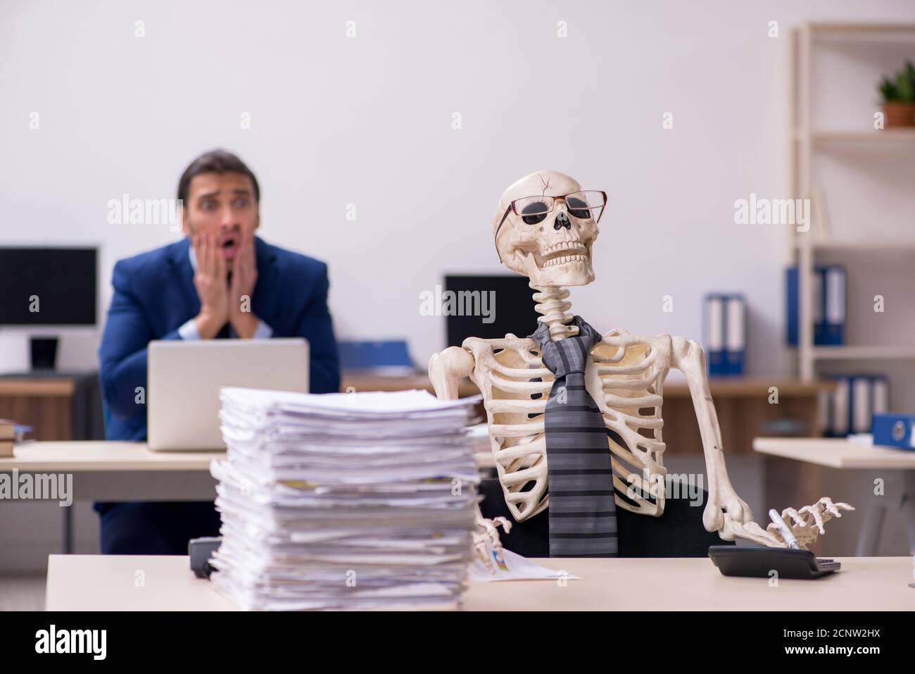 Young employee with skeletons in the office Stock Photo - Alamy