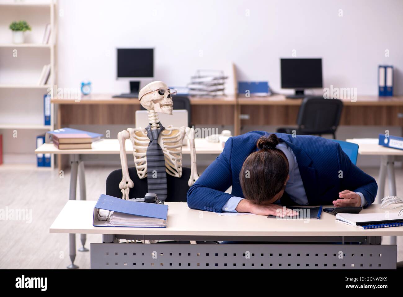 Young employee with skeletons in the office Stock Photo - Alamy