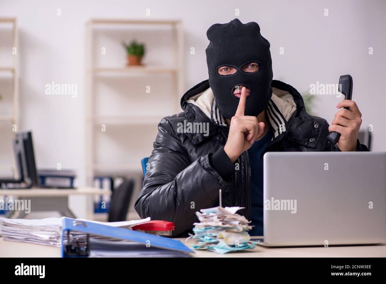 Young male burglar in the office room Stock Photo - Alamy