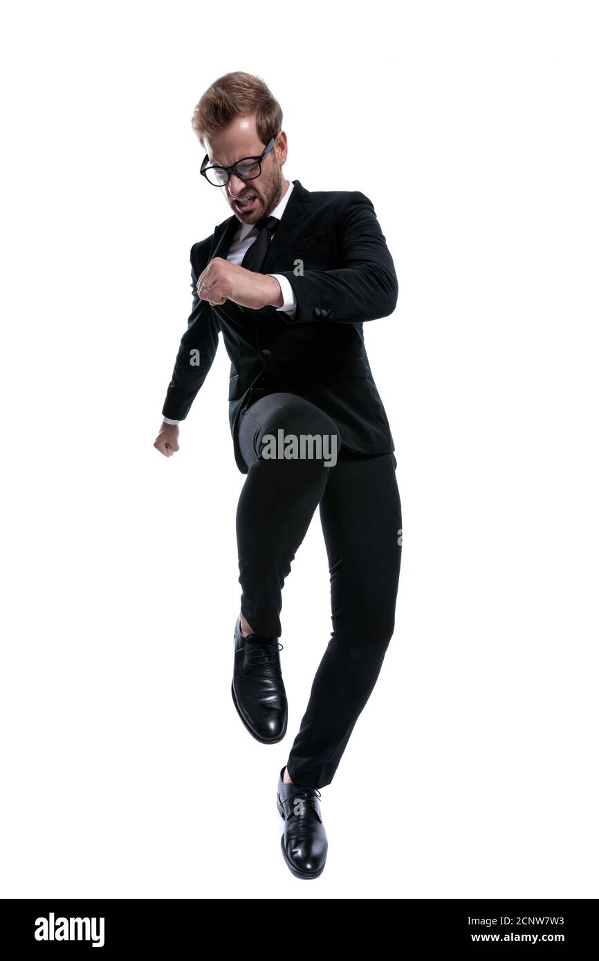 angry dramatic man in black suit holding leg up and kicking, making an ...