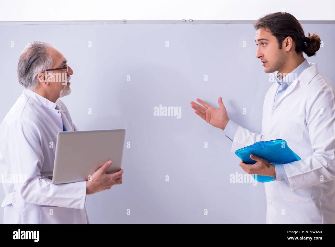 Experienced doctor teaching young assistant using computer Stock Photo ...