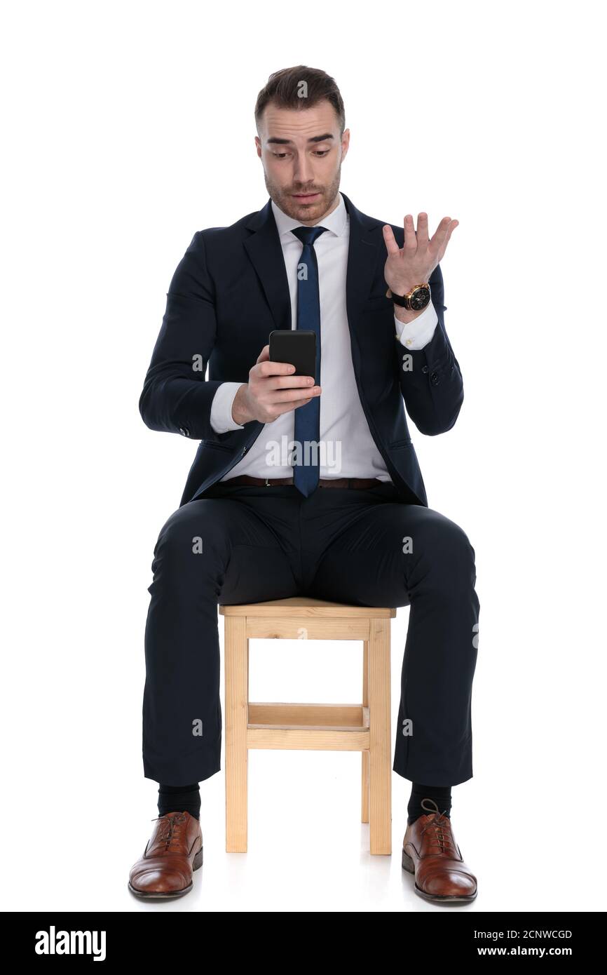 Bothered businessman texting on phone and gesturing while sitting on a ...