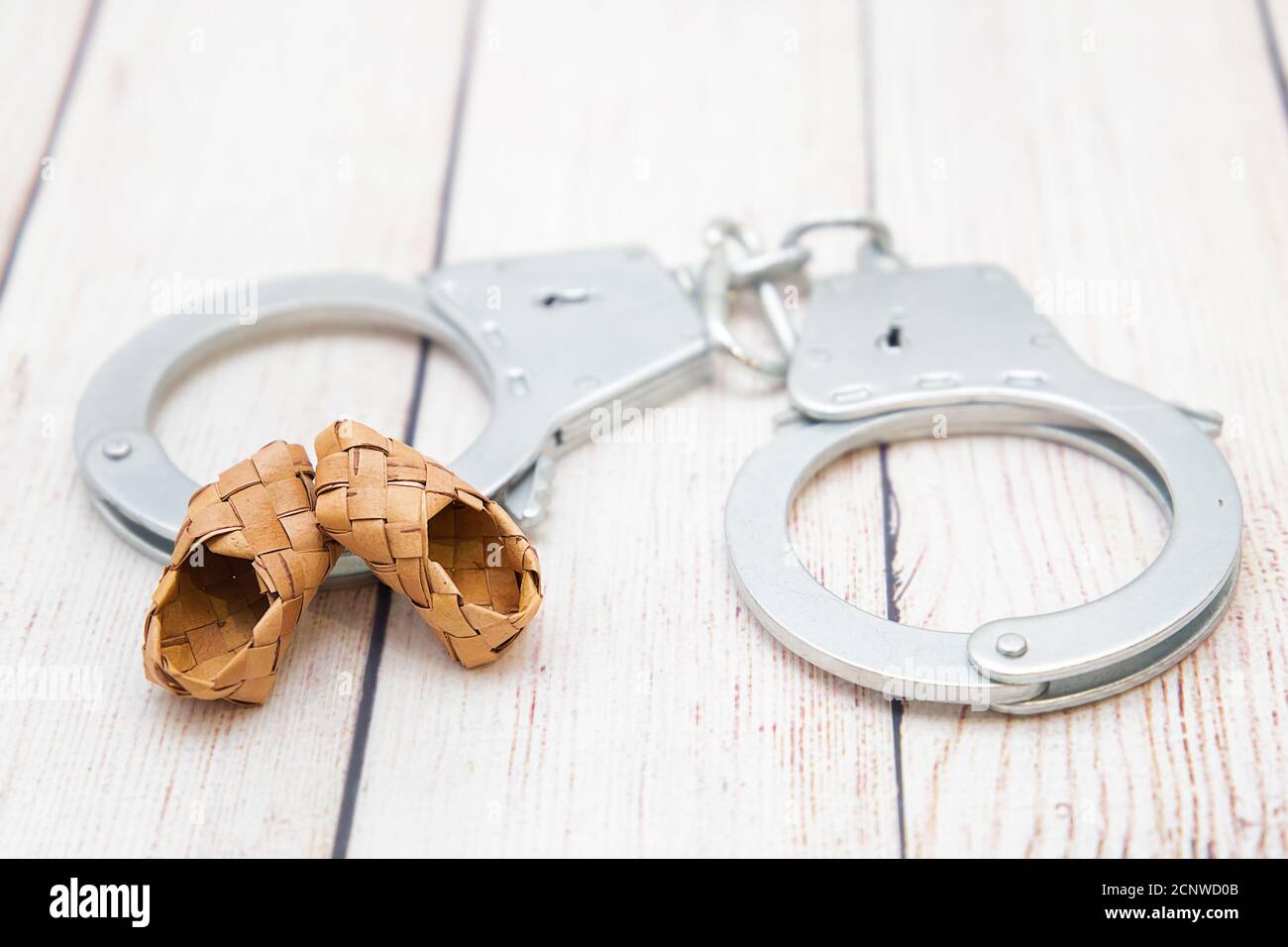 Handcuffs and braided sandals. Poverty drove to jail Stock Photo - Alamy