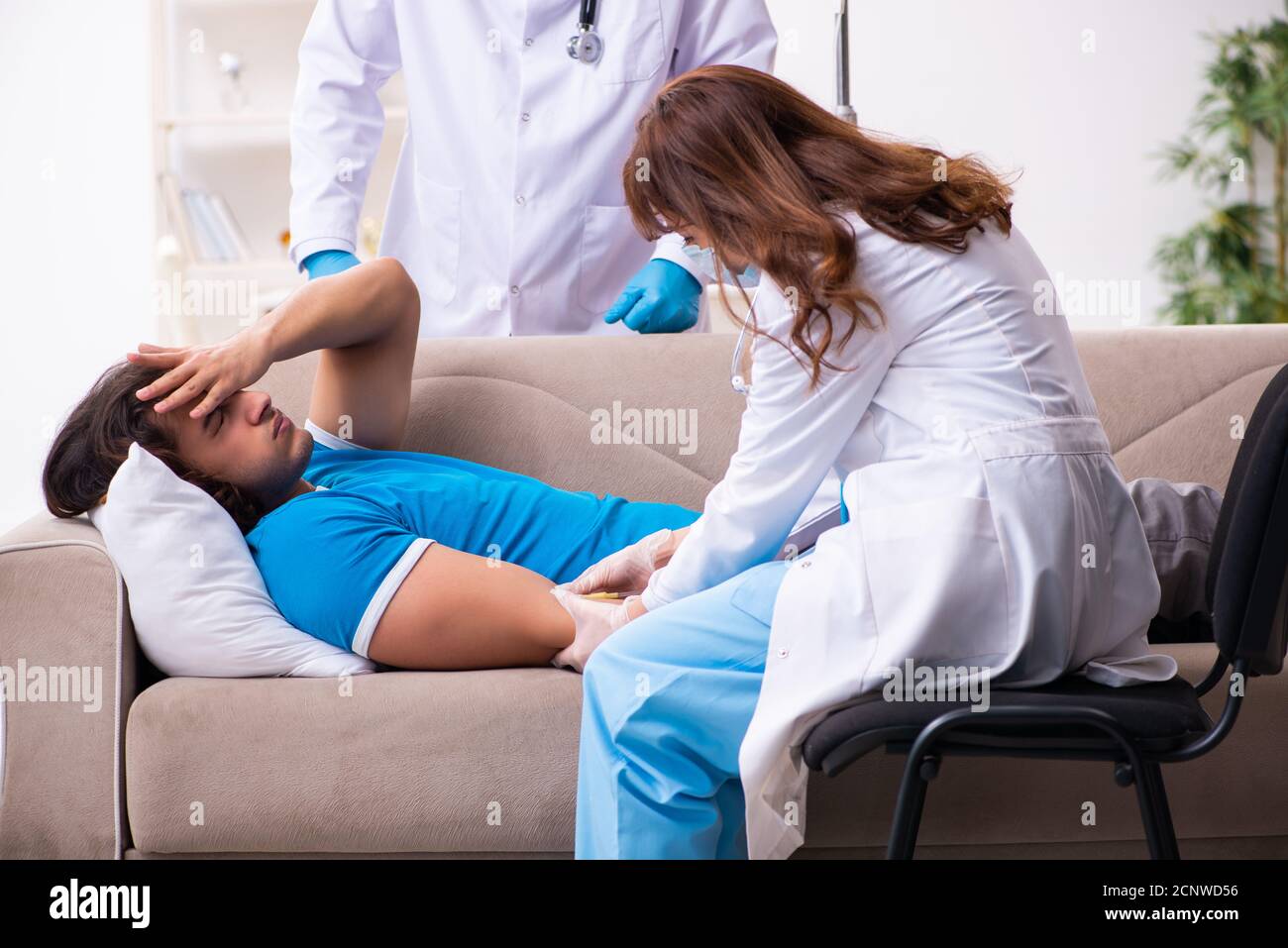 Two doctors visiting sick man at home Stock Photo - Alamy