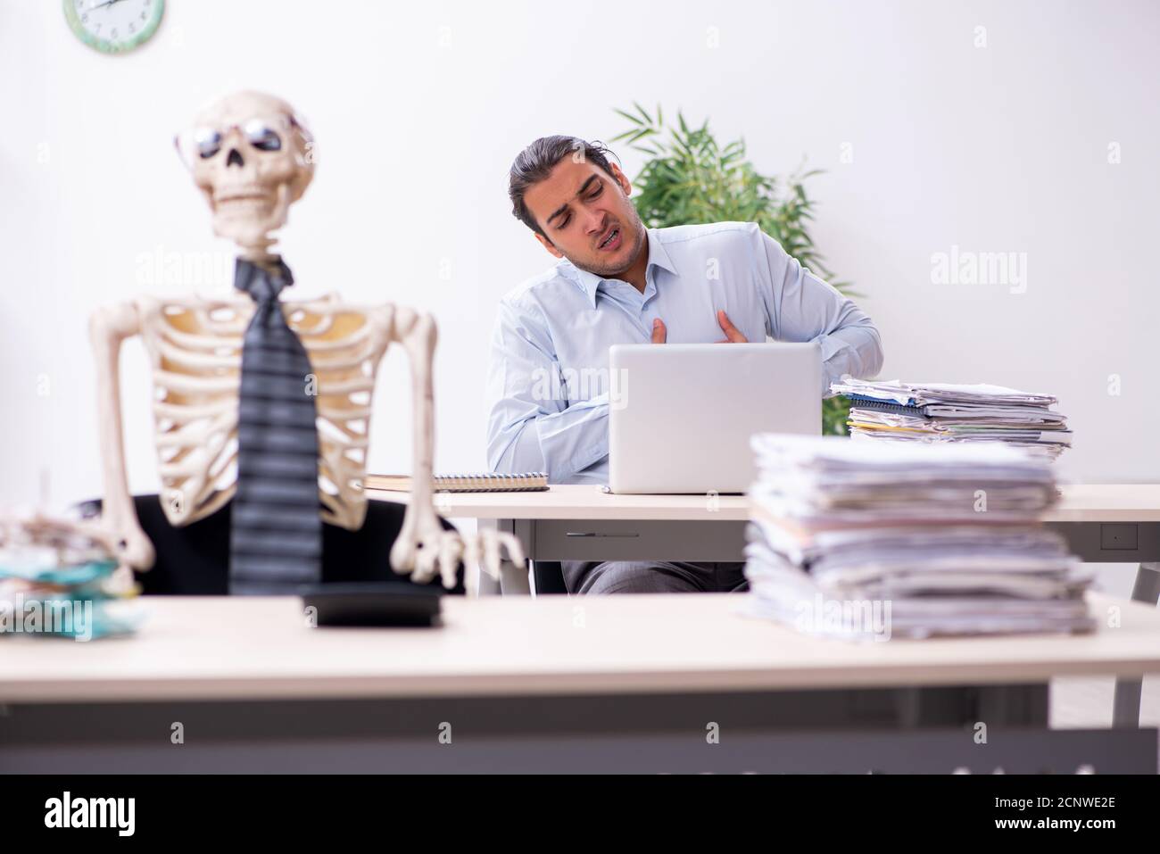 Young employee and skeleton in the office Stock Photo - Alamy