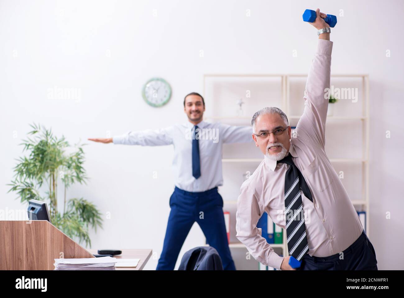 Two employees doing physical exercises at the workplace Stock Photo - Alamy