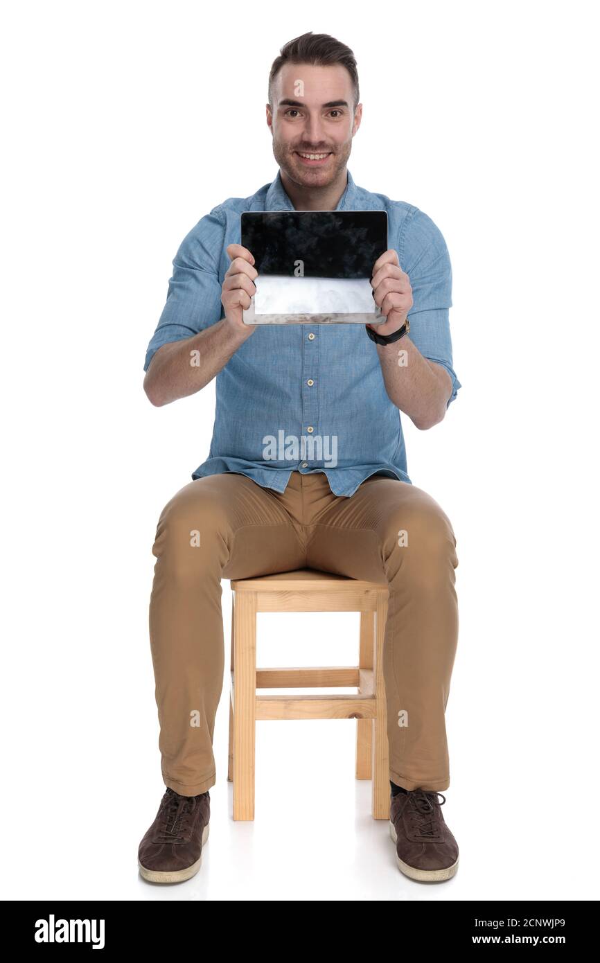 Happy smart casual man holding tablet and smiling while sitting on a ...