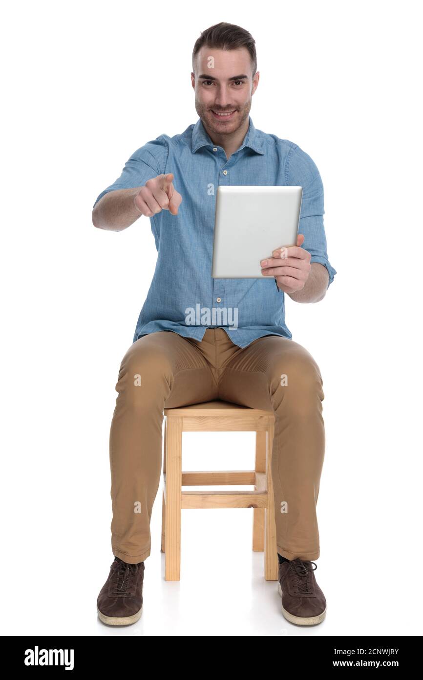 Happy smart casual man pointing forward and holding tablet while ...
