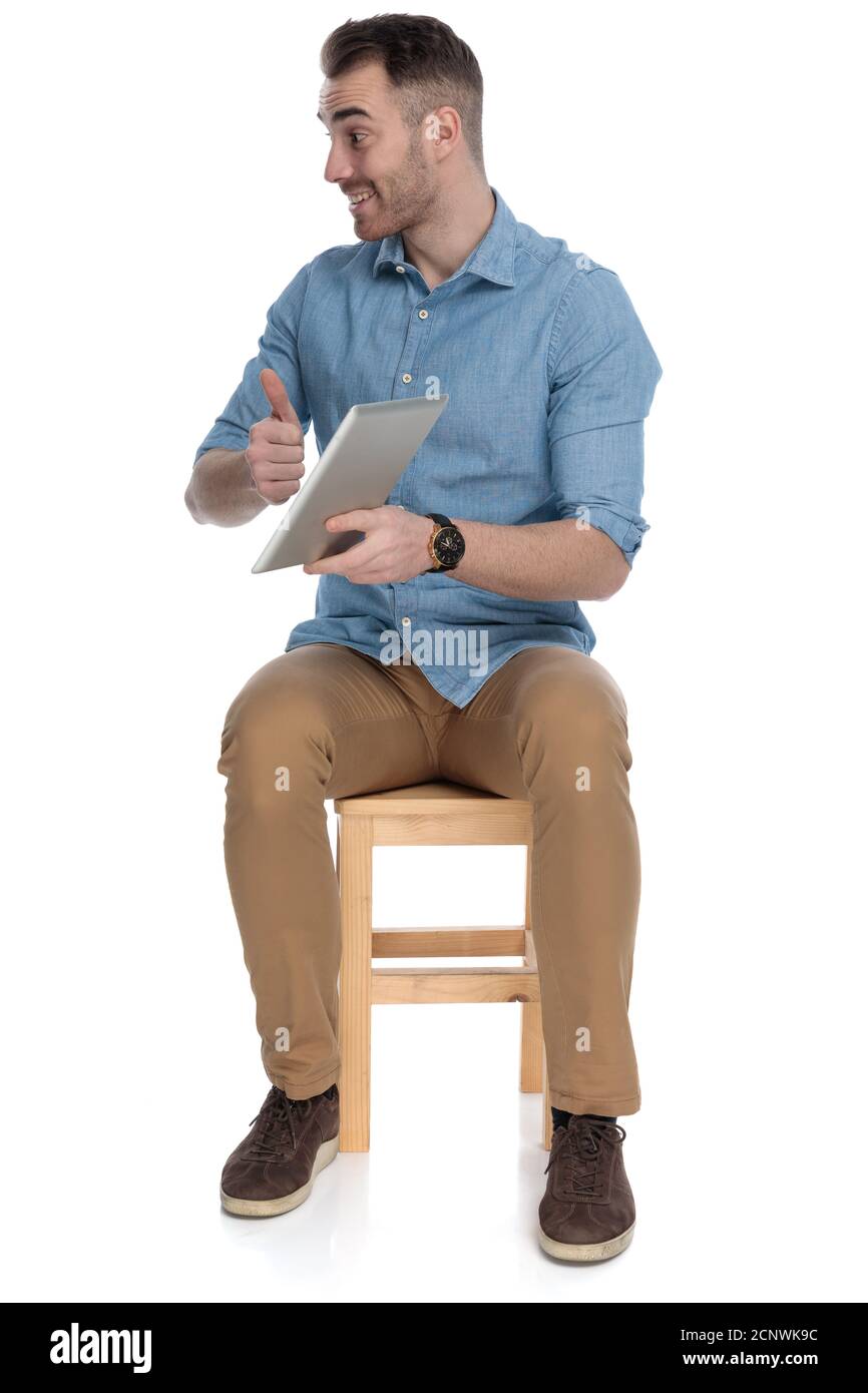 Happy smart casual man holding tablet and gesturing ok while sitting on ...