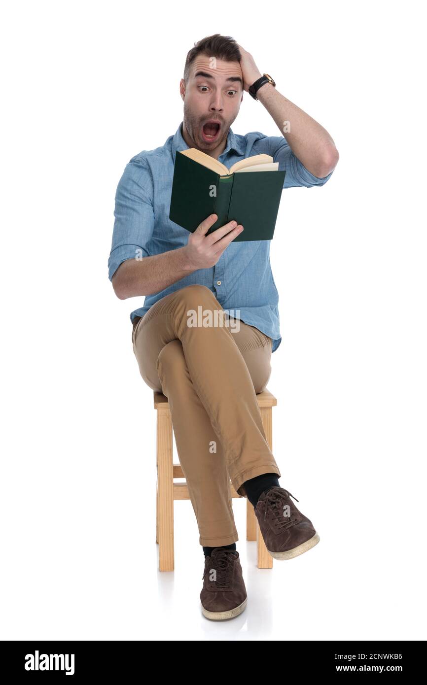 Amazed smart casual man reading a book and shouting, holding hand on ...