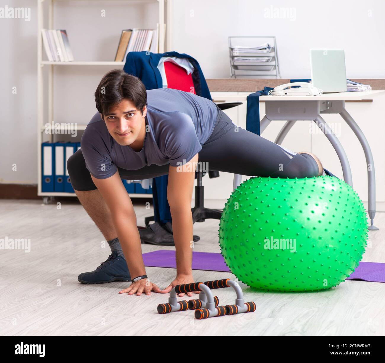 The young male employee exercising in the office Stock Photo - Alamy