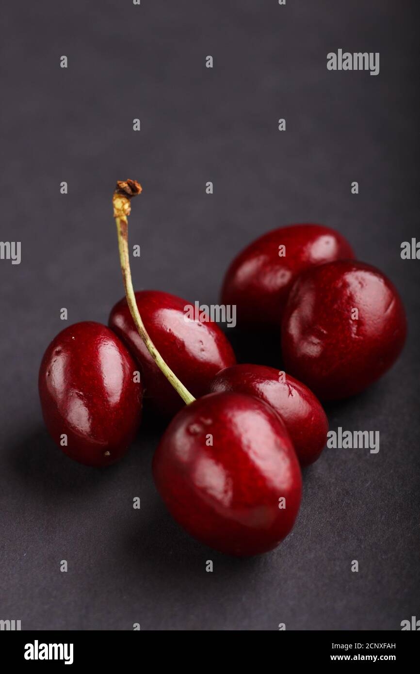 Ugly weird red sweet cherry on black background. side view, close up ...