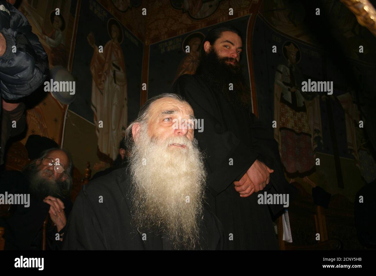 Elderly monk with long white beard inside a Christian Orthodox church ...