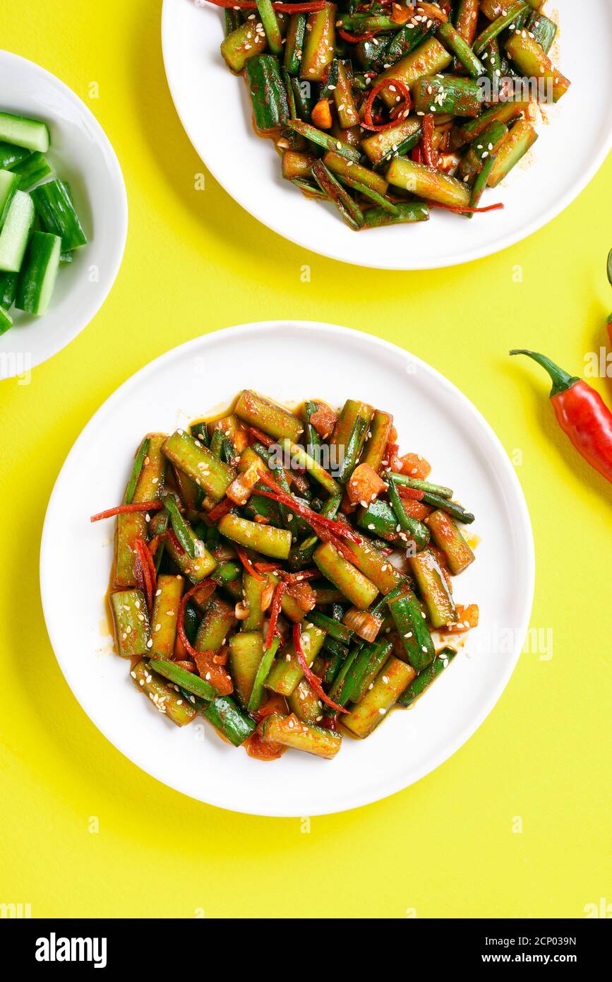 Korean style cucumber kimchi on plate over yellow background. Top view ...