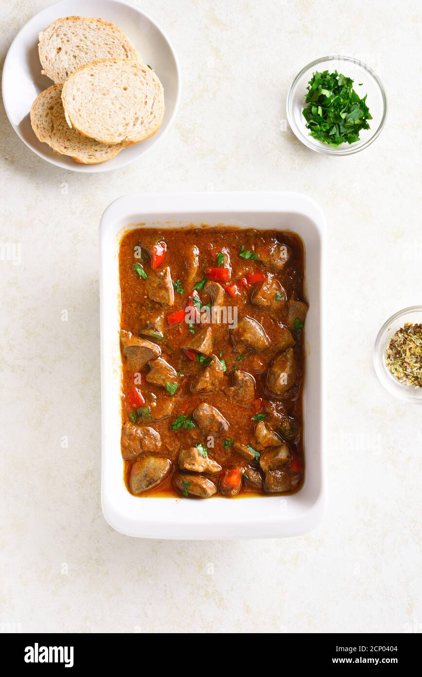 Peri-peri chicken livers in baking dish over light background. Top view ...