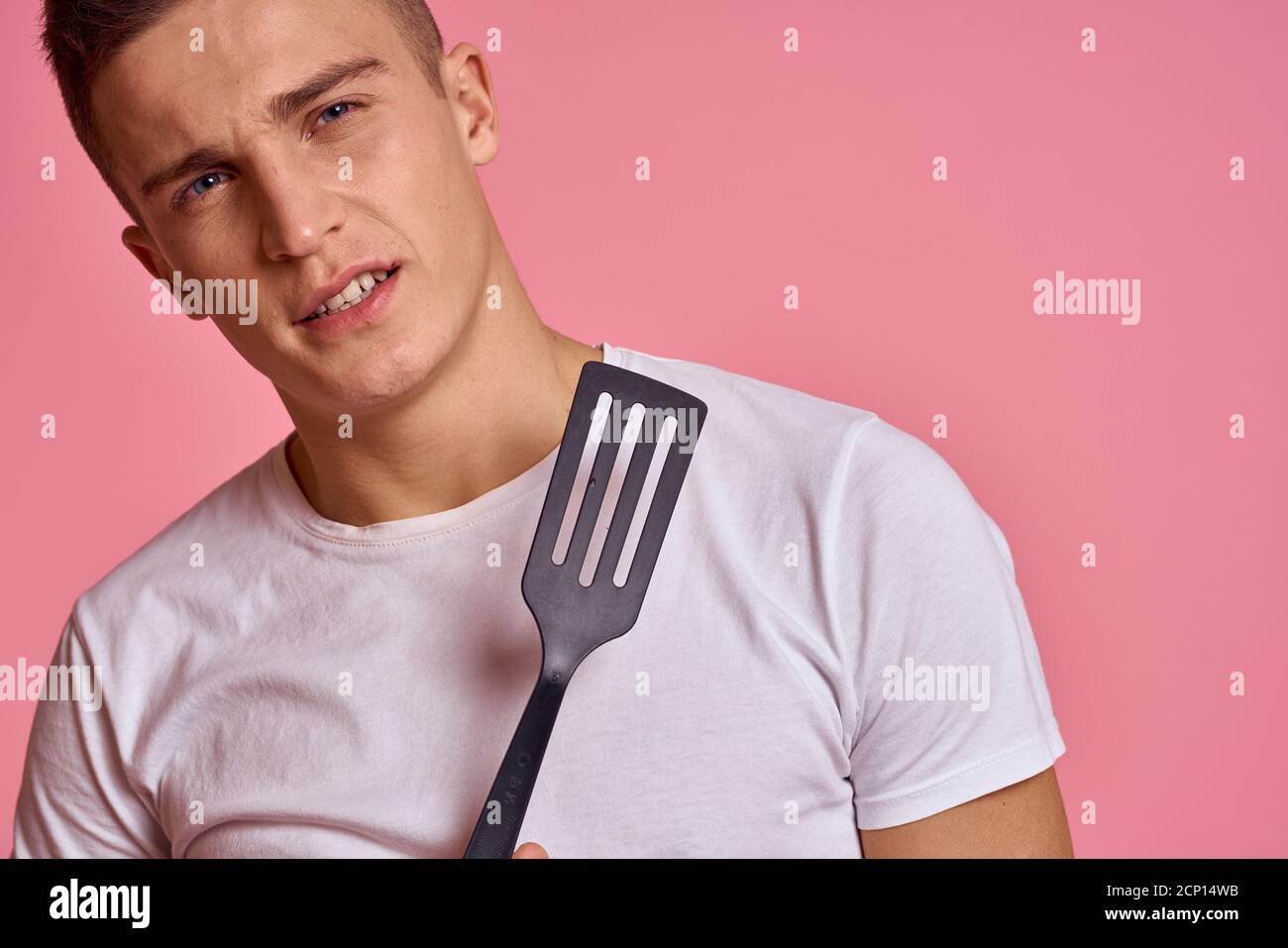 Man with kitchen tools on pink background spatula for cooking model ...