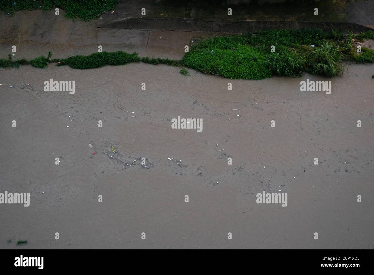 River canal in a big city. Sewage after rain carries garbage along the ...