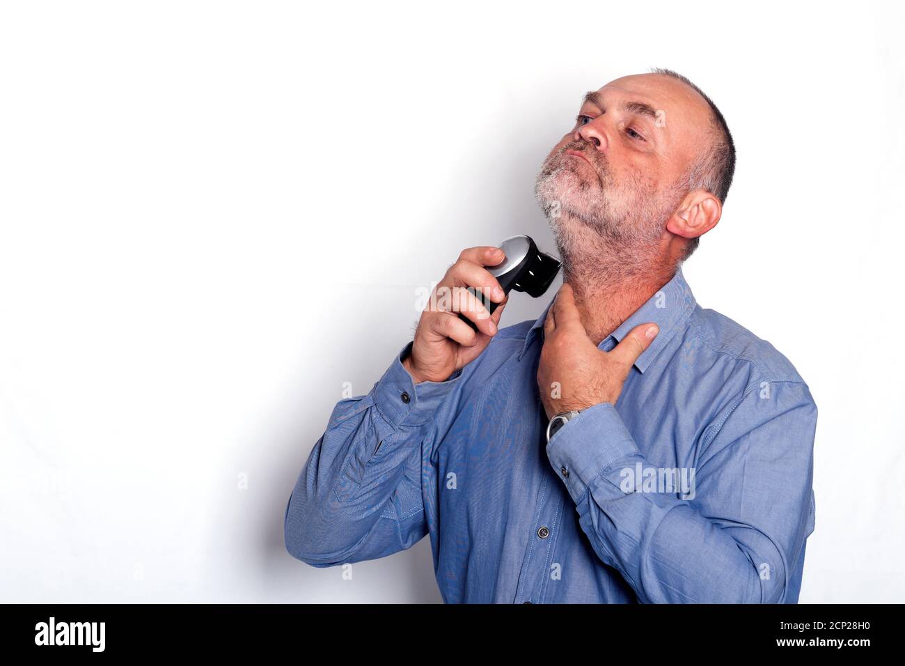 Portrait of man shaving his beard with electric shaver against white ...