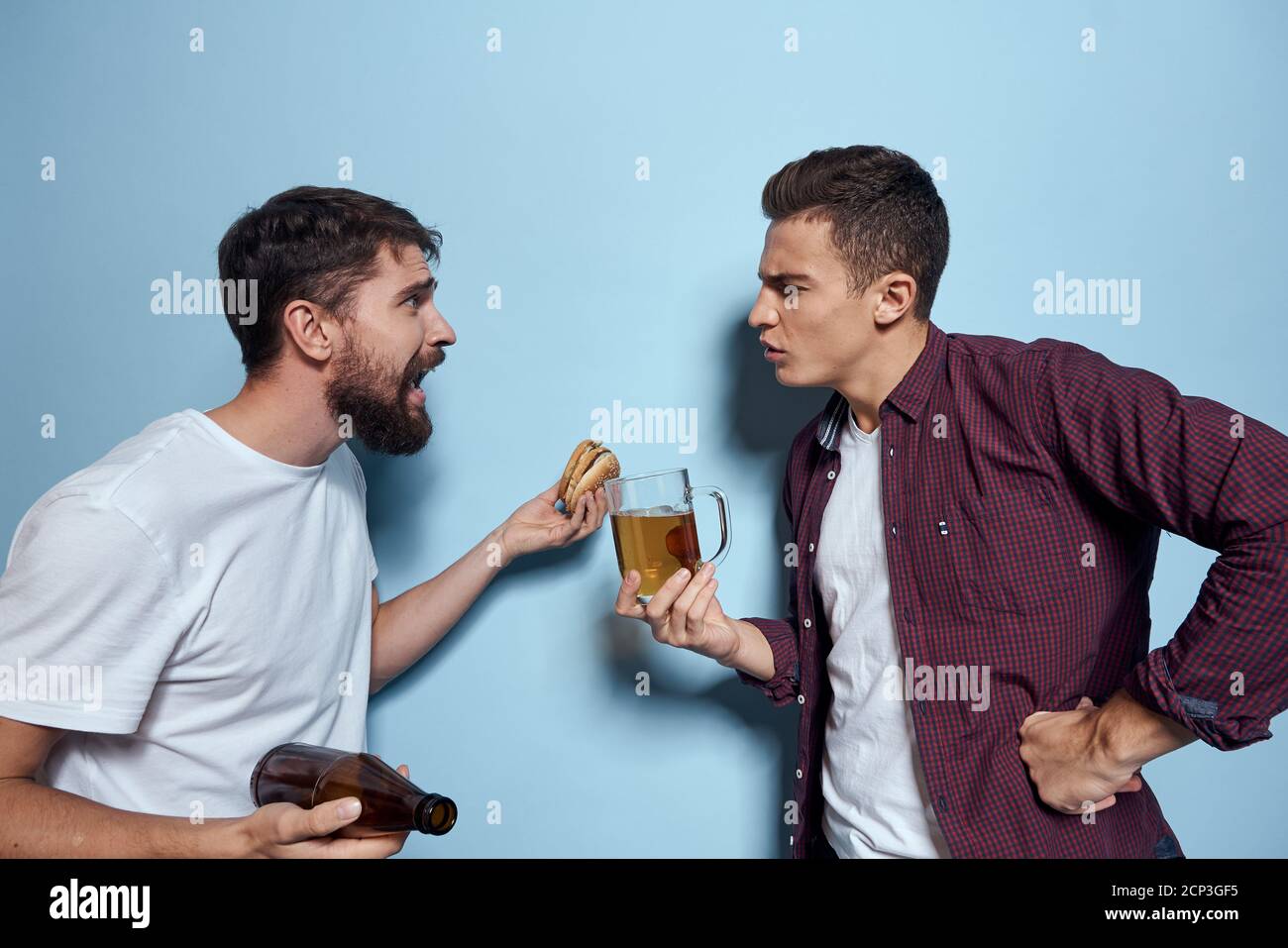 Two cheerful drunk friends drinking beer lifestyle emotions on a blue ...