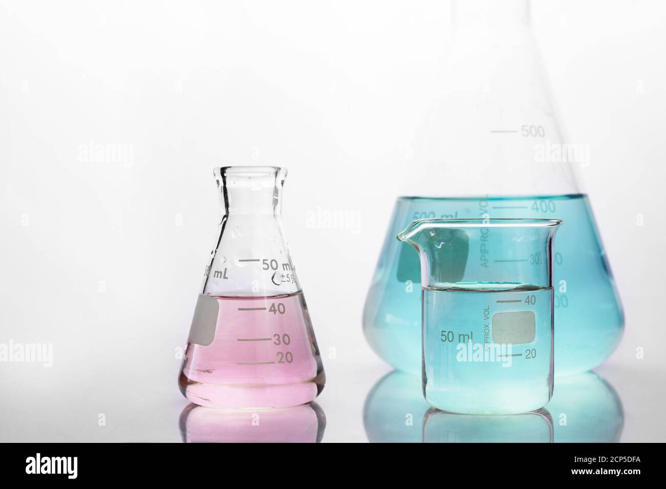 pink and blue solution in beaker and flask in white chemistry science ...