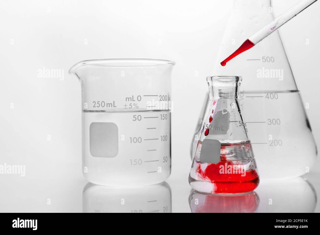 red drop of chemical solution in glass flask in white research science ...