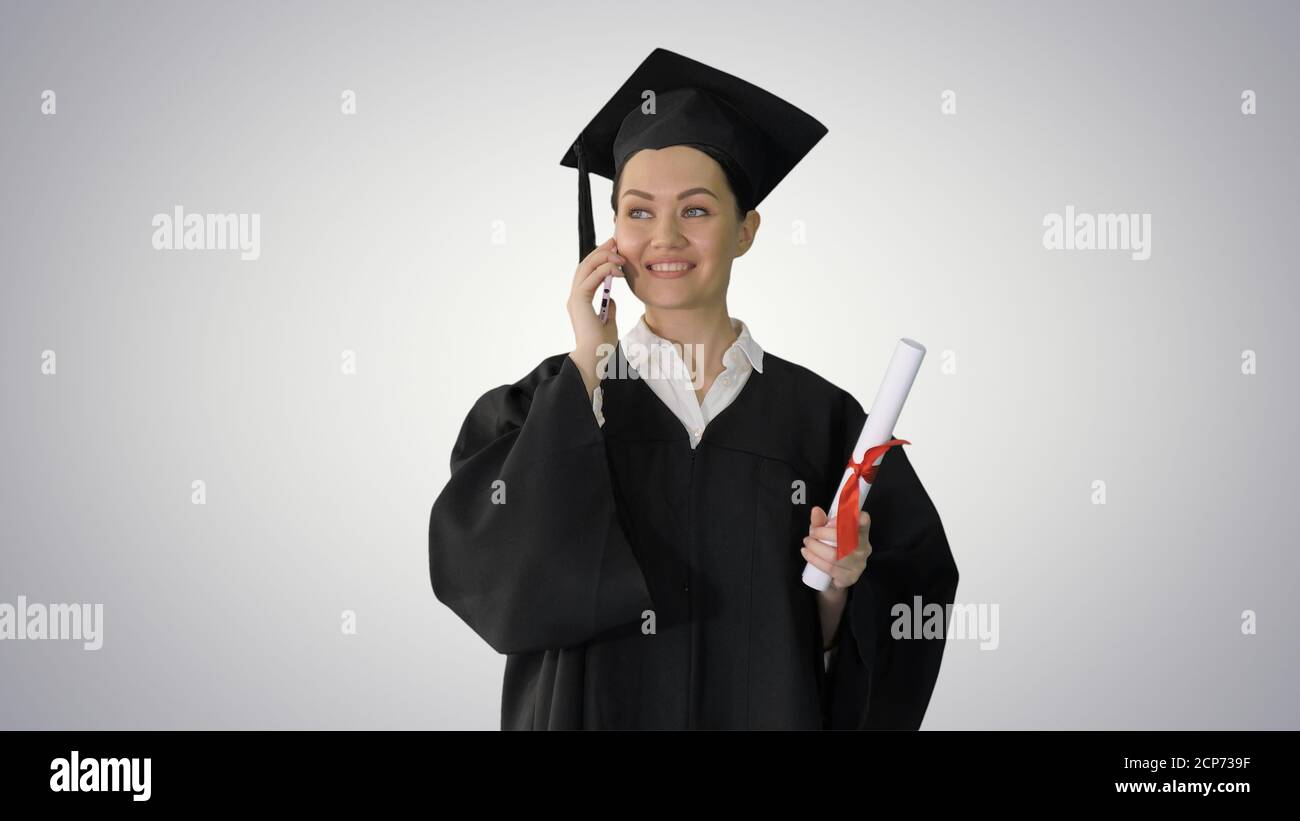 Emotional female student in graduation robe talking on the phone Stock ...
