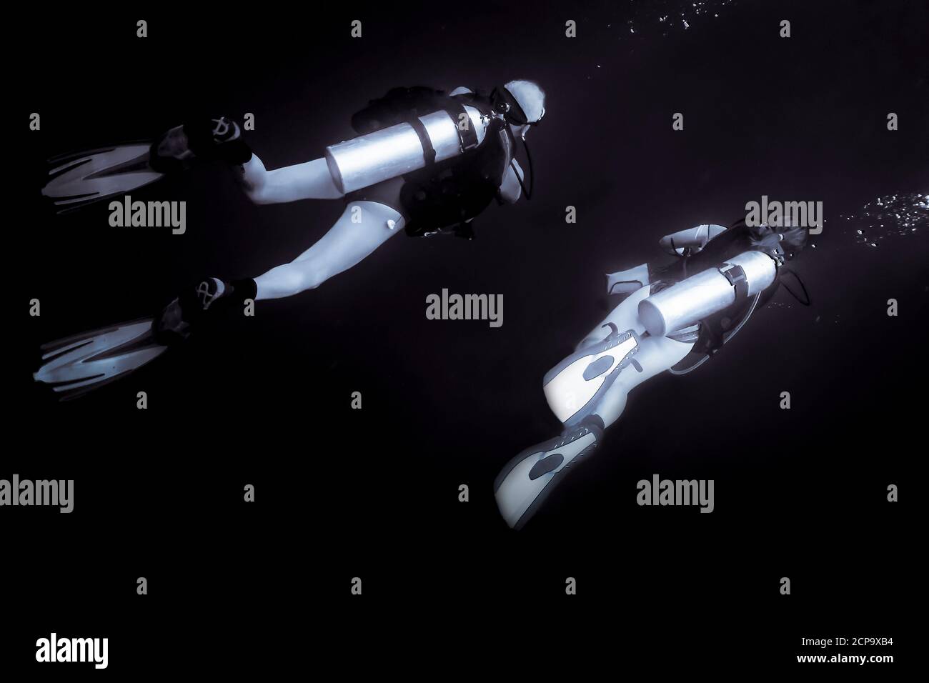 Divers a man and a woman floating above the dark abyss of the ocean ...