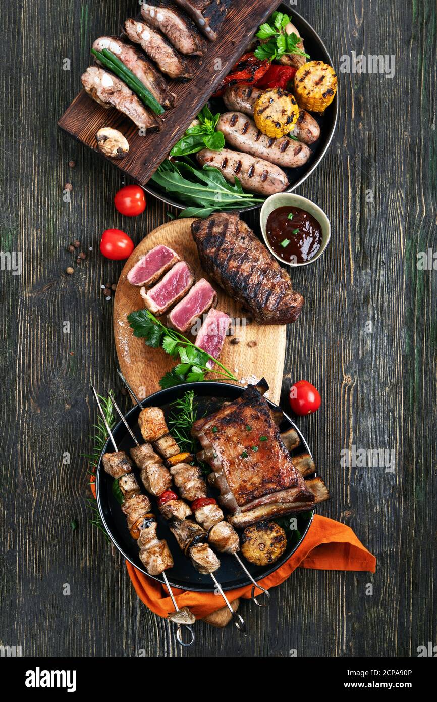 Assorted grilled meat with vegetables on wooden background. Barbecue ...