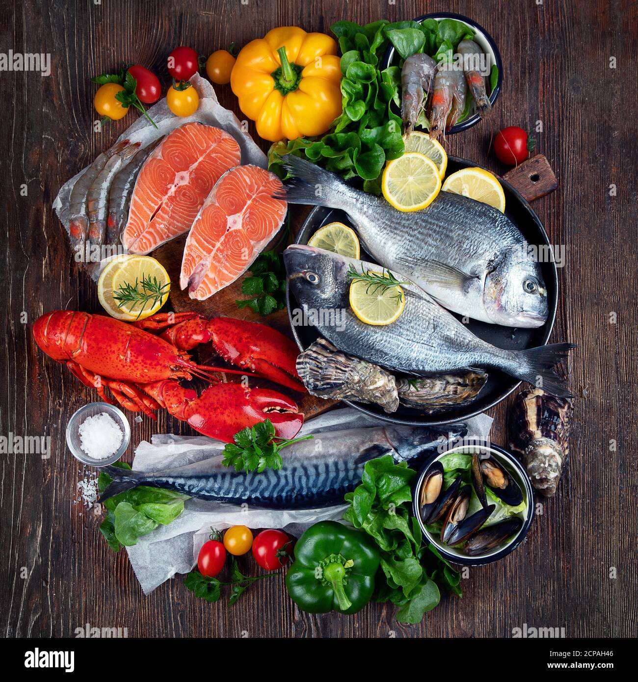 Fresh fish and seafood with herbs, spices and vegetables on rustic ...