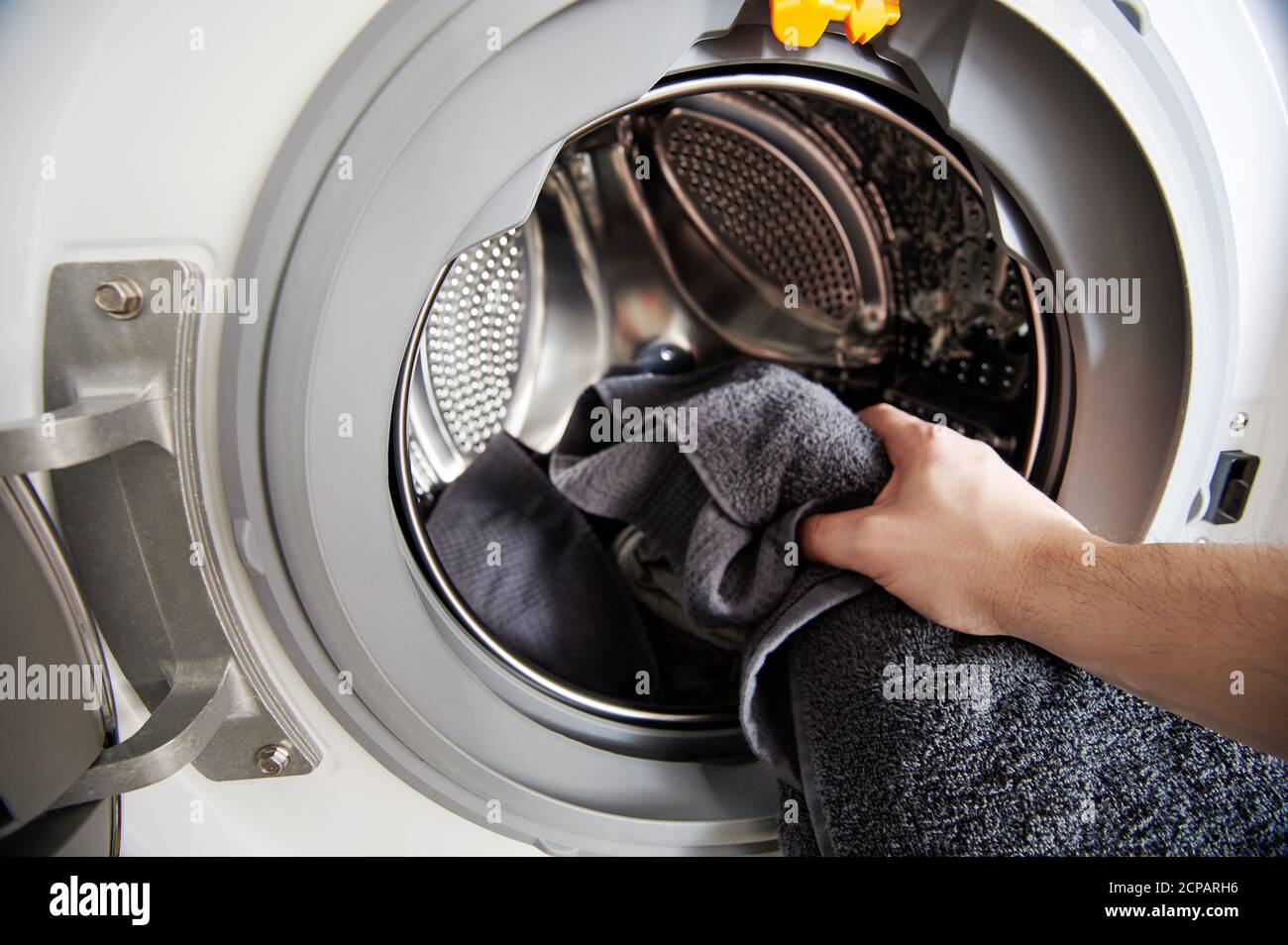 Loading dirty cloth in washing machine close up view Stock Photo - Alamy