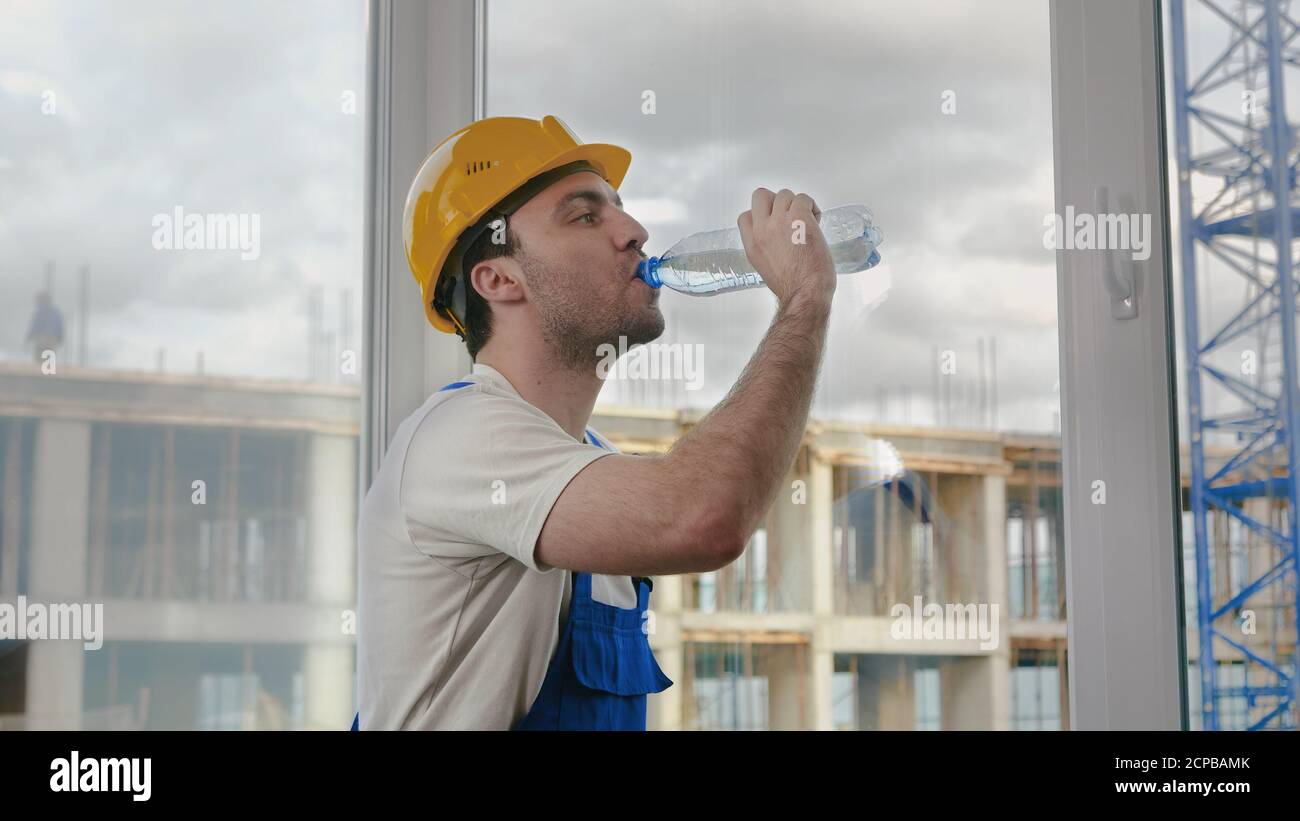 Construction in helmet worker drinking water Stock Photo - Alamy