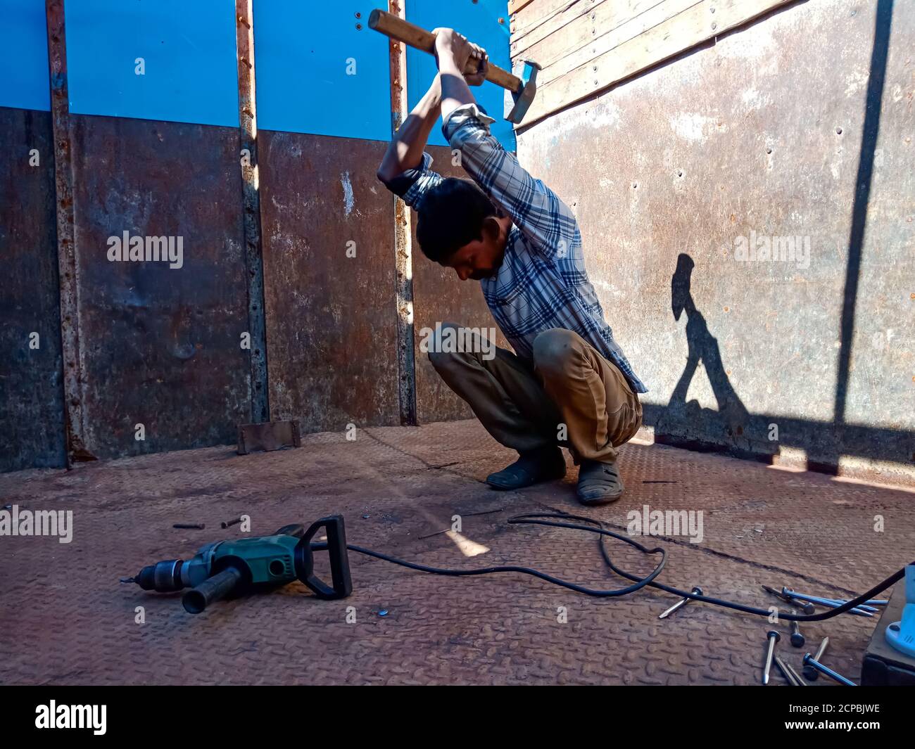 DISTRICT KATNI, INDIA - DECEMBER 14, 2019: An asian Mechanic hammering ...