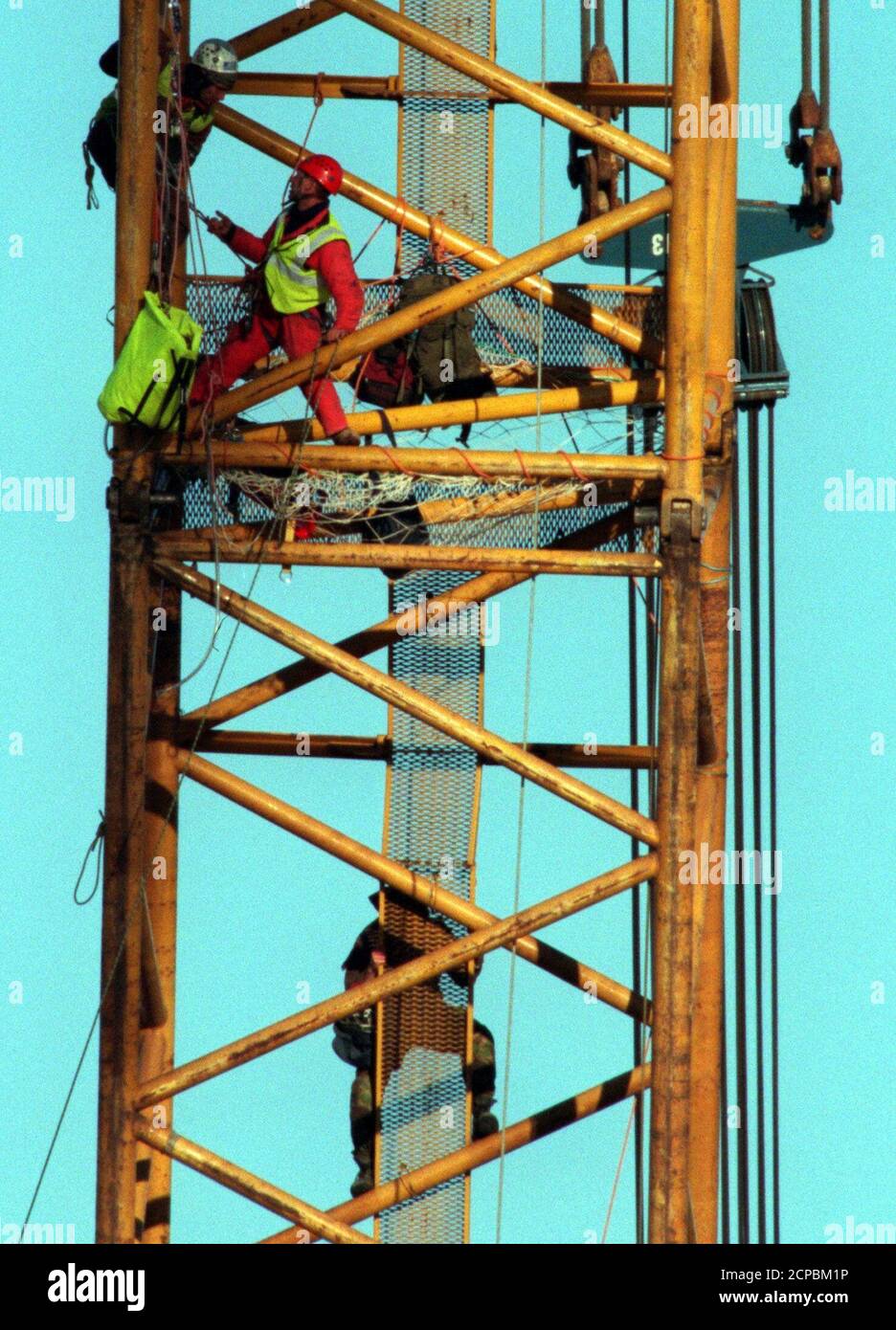 A protester (bottom) scales a crane on the Millennium dome site as ...