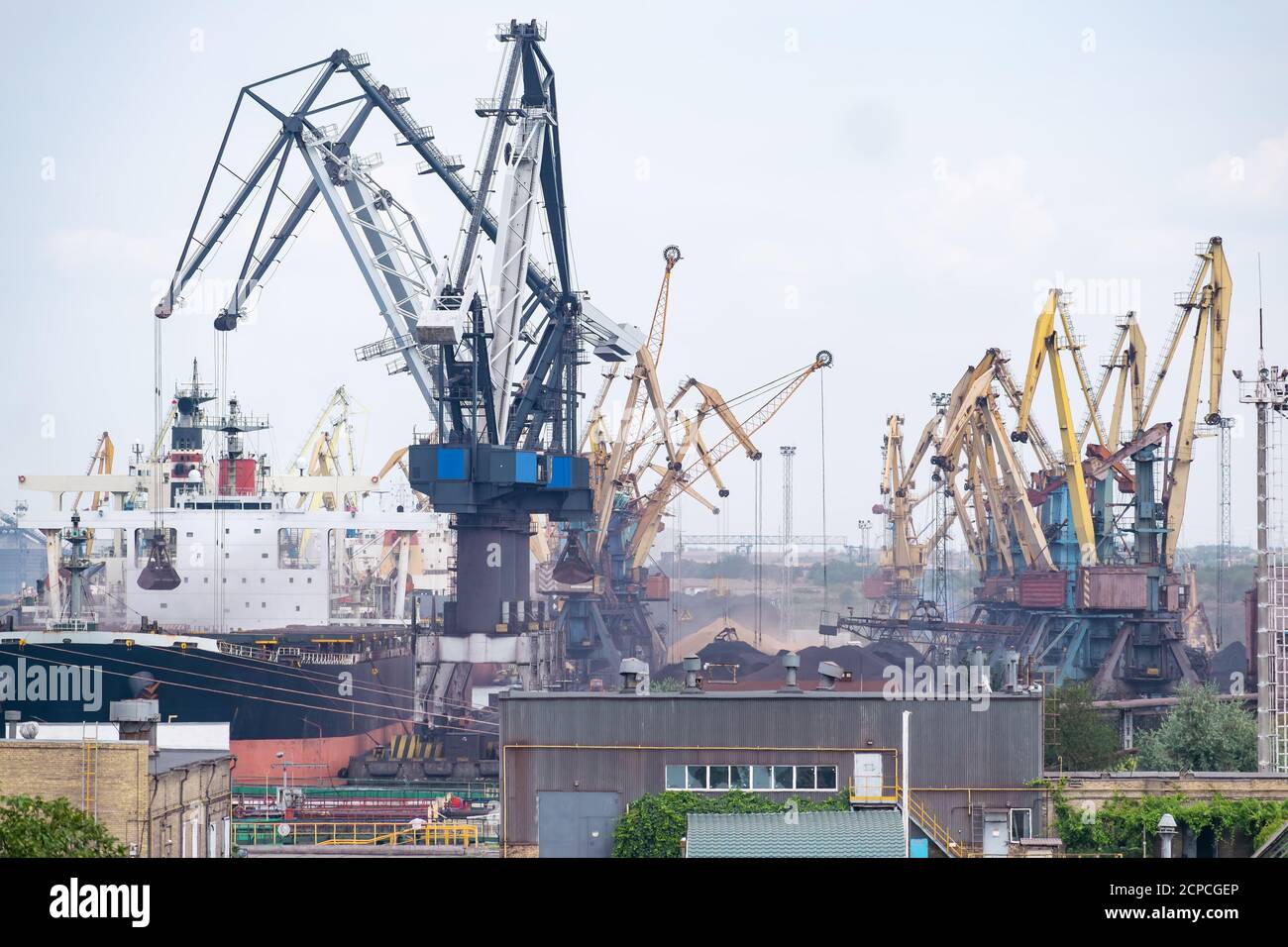 Cranes at the cargo sea port loading the bulk carrier with iron ore or ...