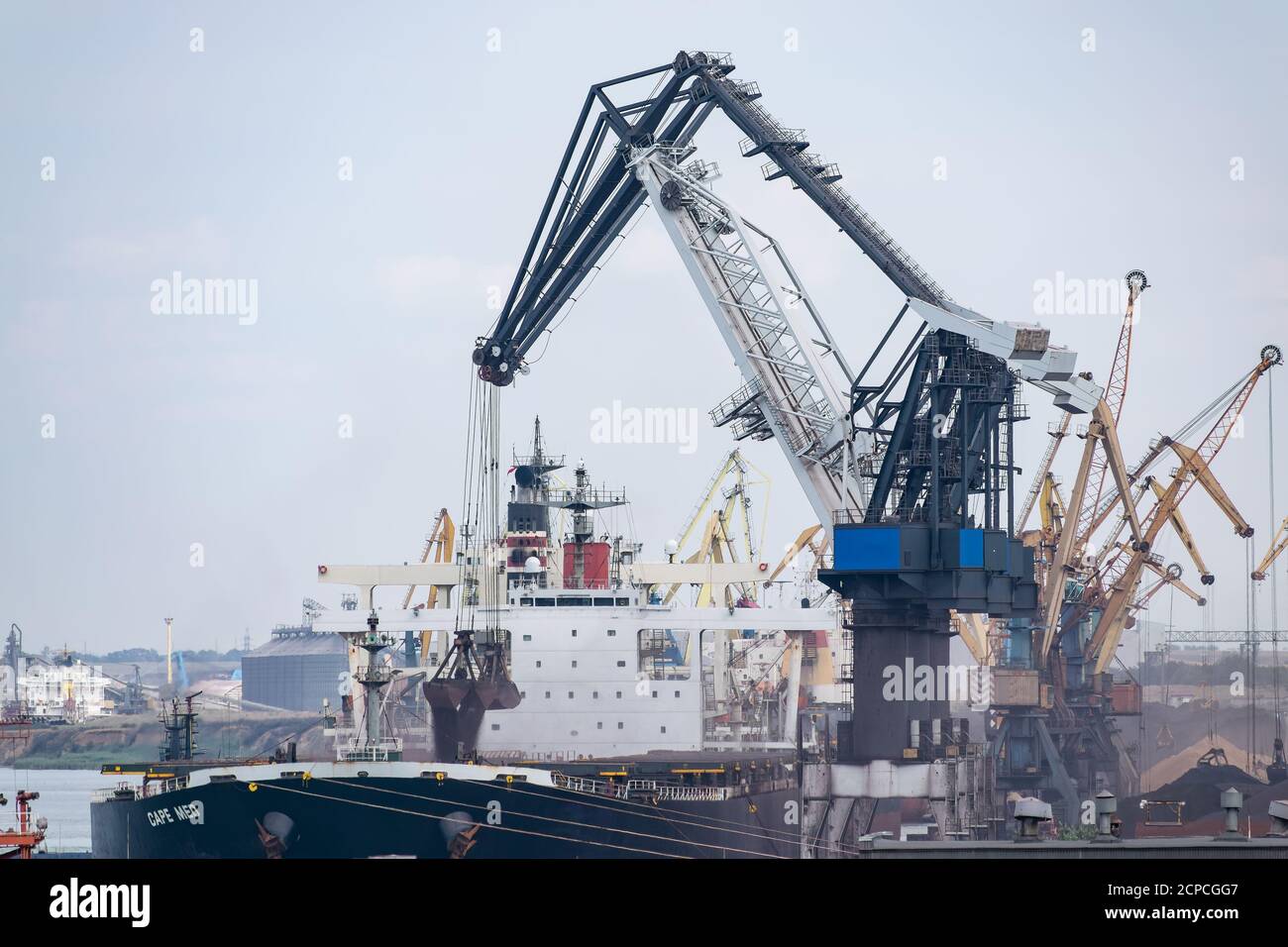 Cranes at the cargo sea port loading the bulk carrier with iron ore or ...
