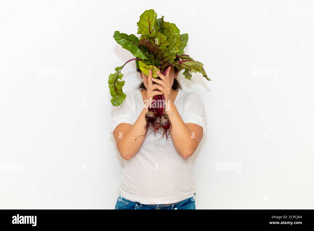 Real young man with a bunch of radishes covering his face. Isolated on ...