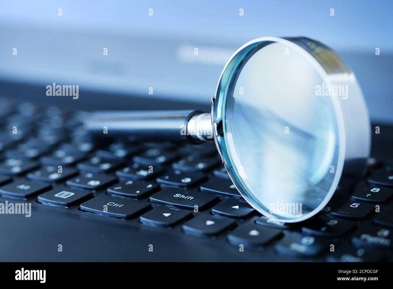 Magnifier on a computer keyboard, with a blurred background and shallow ...