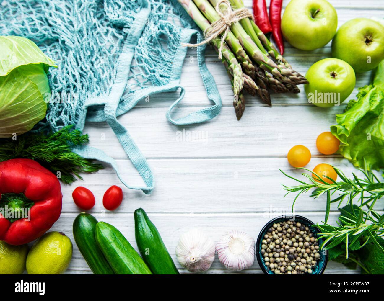 Fresh vegetables and fruits with a string bag on a white wooden ...