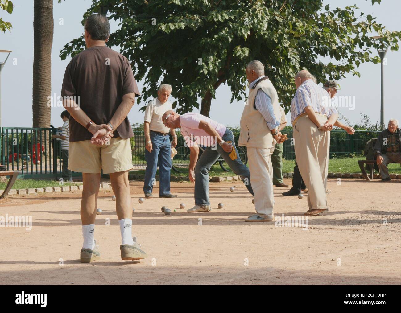 Petanque game on the promenade. The player points to the target. The ...