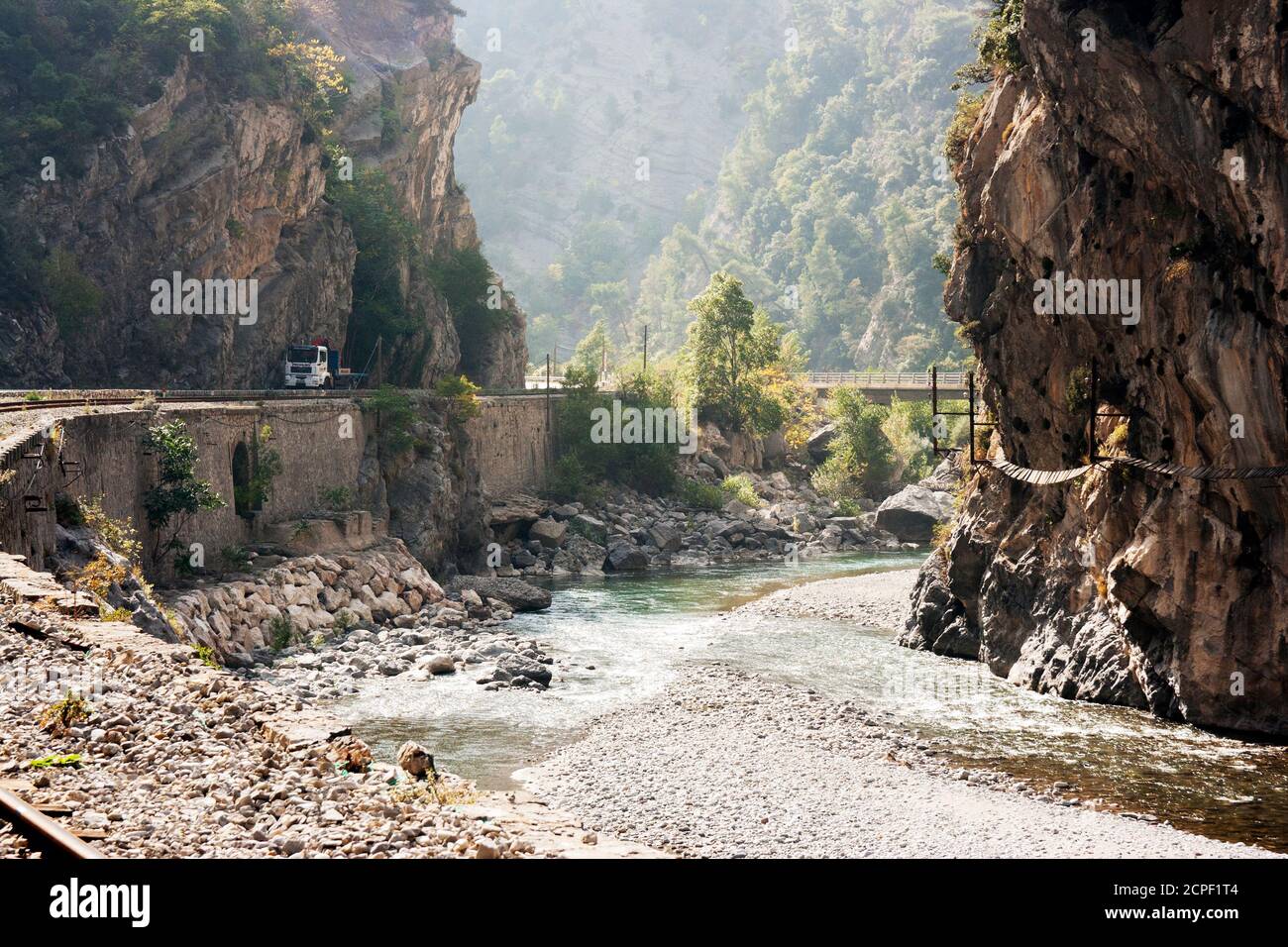 Torn suspension bridge on the rock wall in the valley of river Loup ...