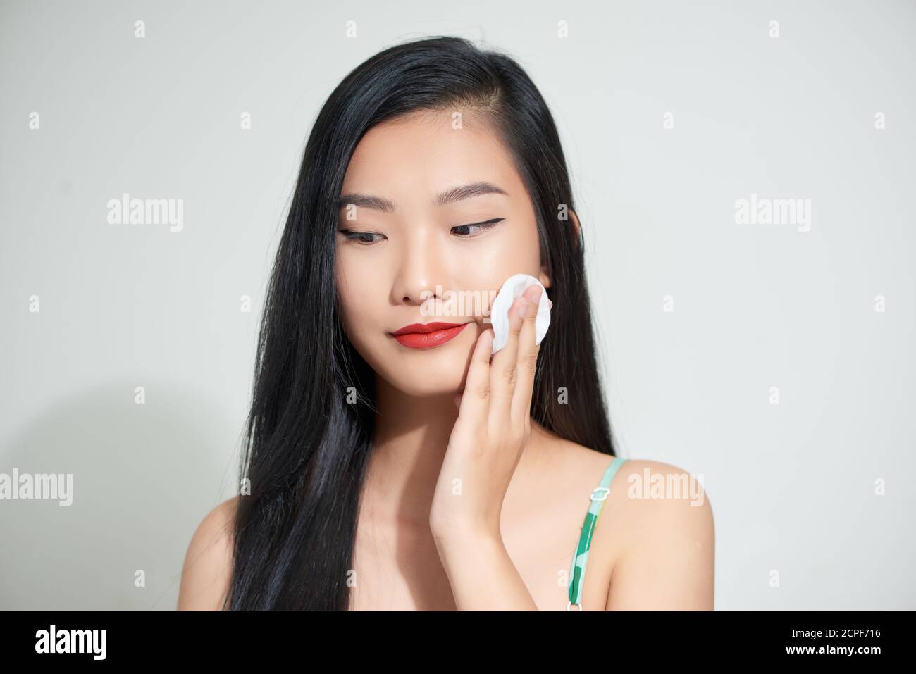 Pretty beauty young Asian woman cleaning her face with cotton pad over ...